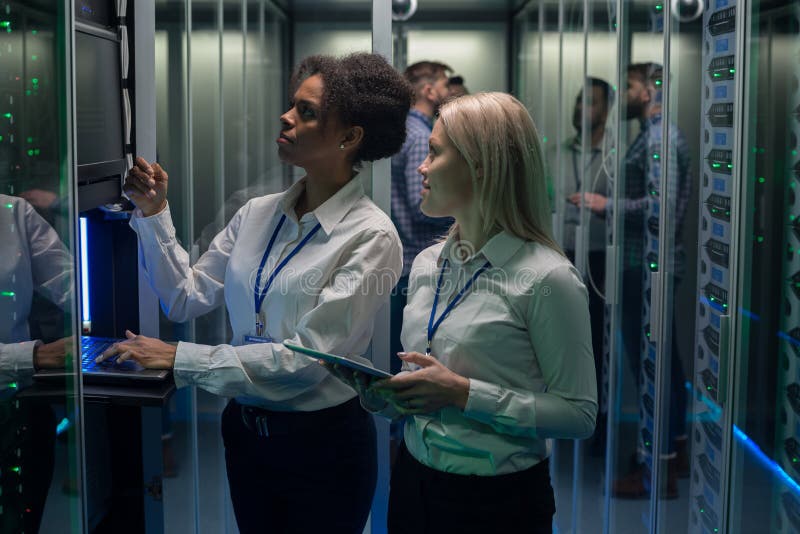 Two Women are Working in a Data Center with Rows of Server Racks Stock ...