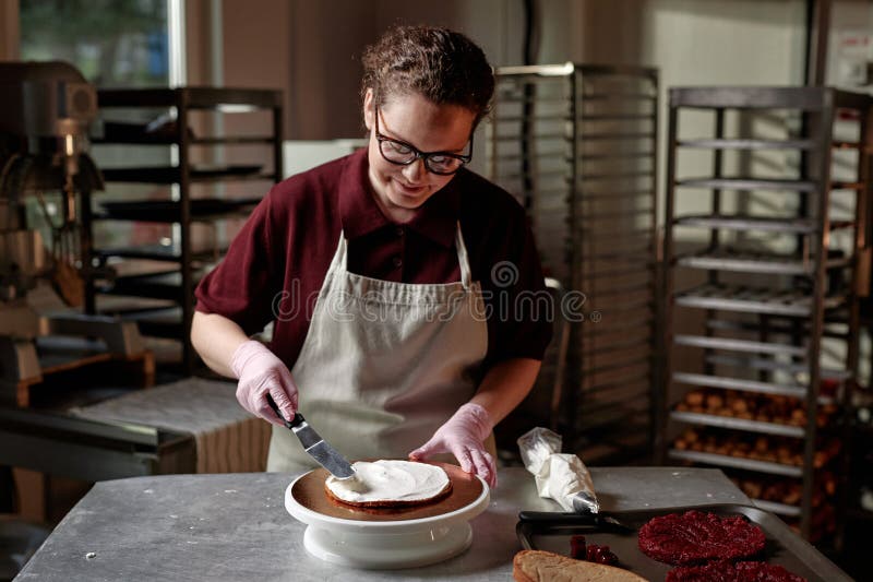 Young Female Confectionary Chef Making Cake Spreading Layer of Cream in ...