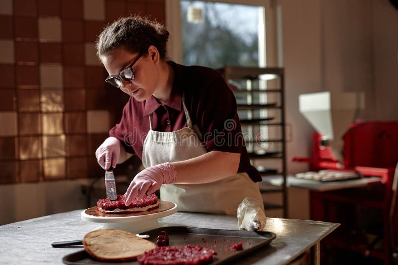 Young Female Confectionary Chef Making Cake Spreading Jam Over Layer in ...
