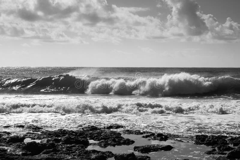Medium Waves Crashing on the Rocks, Grey Sky with Clouds Stock Image ...
