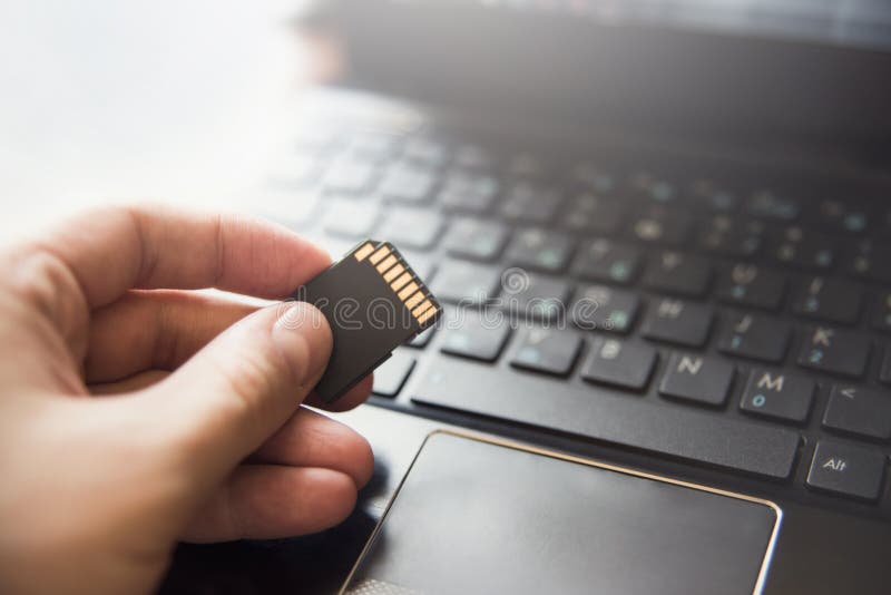 Memory Card in Hand, Laptop, Keyboard. Flash Drive Information. Data ...