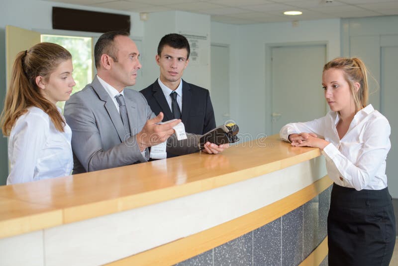 Men Behind Reception Desk Looking at Computer Stock Photo - Image of ...