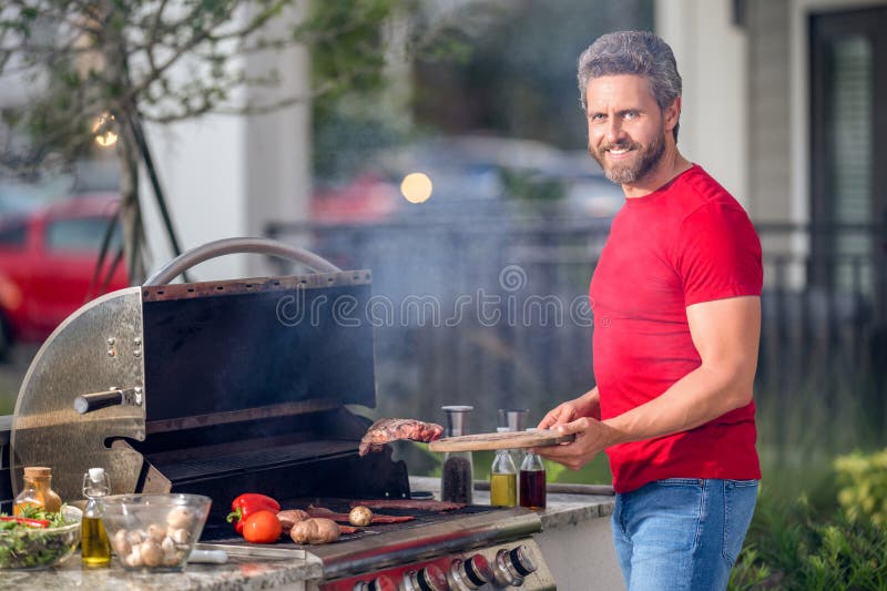Men Cooking Steak on Barbecue Grill in Yard. Cook at a Barbecue Grill ...
