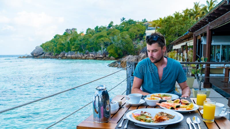 Men Drinking Coffee at a Breakfast Table with a View Over the Ocean La ...