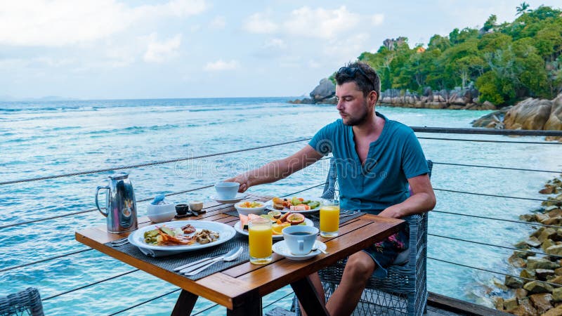 Men Drinking Coffee at a Breakfast Table with a View Over the Ocean La ...