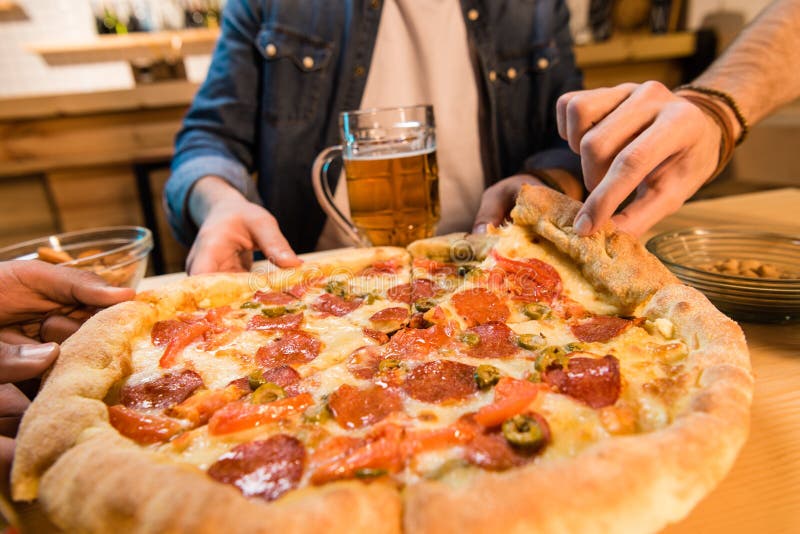 Men eating pizza stock photo. Image of evening, alcohol - 104988922
