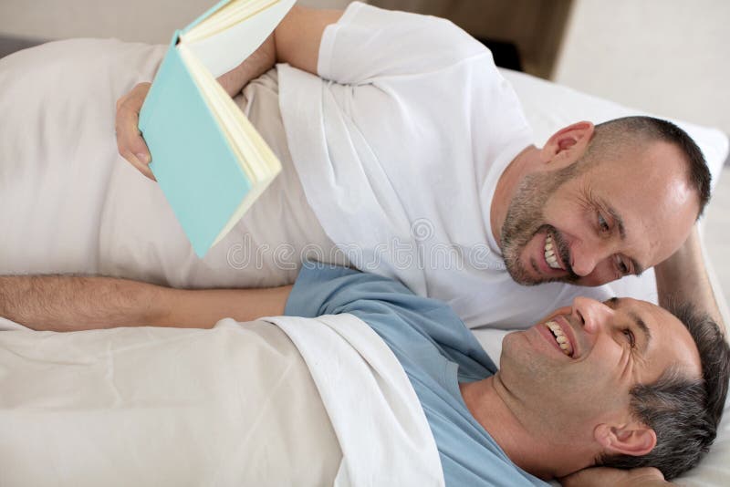 Men Lying on Bed Together while Looking Reading Book Stock Photo ...