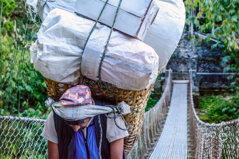Men in Nepal is Crossing the Bridge with a Heavy Load on His Back ...