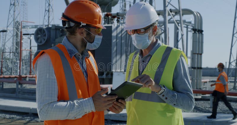 Engineers in Masks Using Tablet on Power Station Stock Image - Image of ...