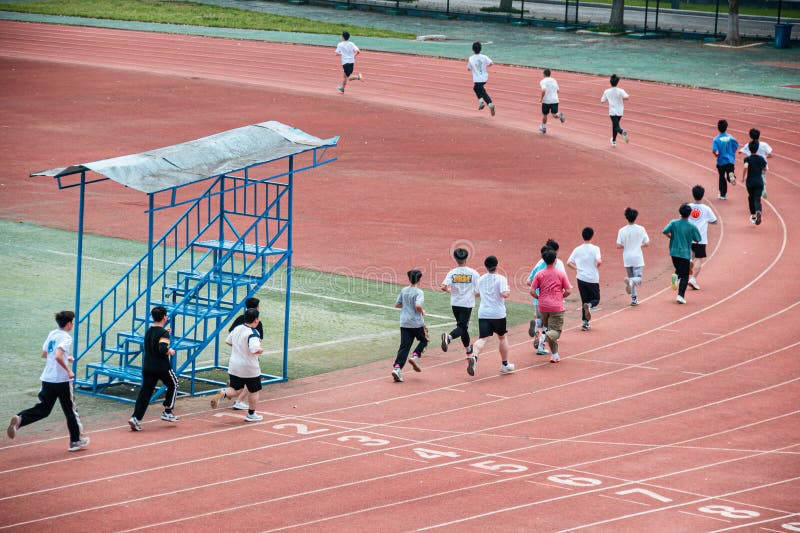 Men Running on a Track in an Empty Stadium, with a Blue Platform ...