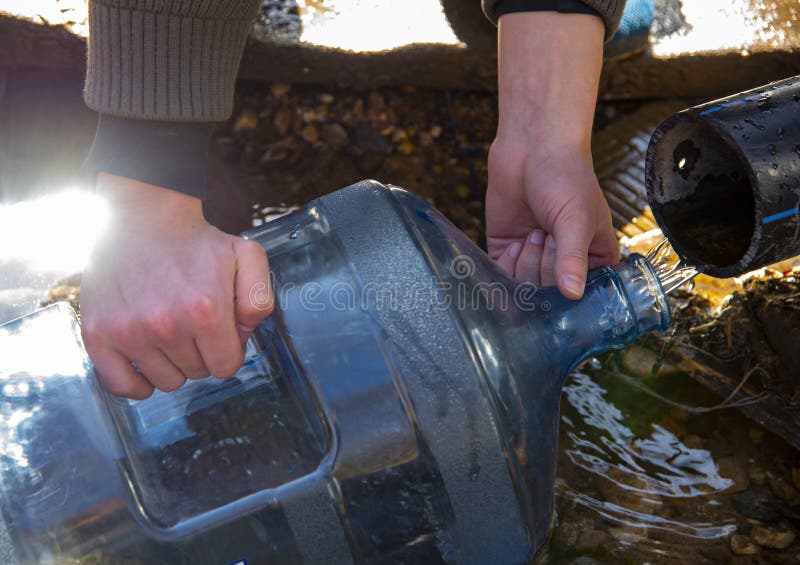 Men`s Hands Fill a Plastic Bottle with Water from a Spring. Stock Image ...
