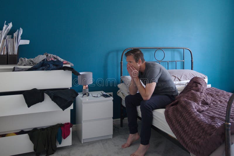 Man Sitting on Edge of Bed Looking Anxious Stock Photo - Image of ...