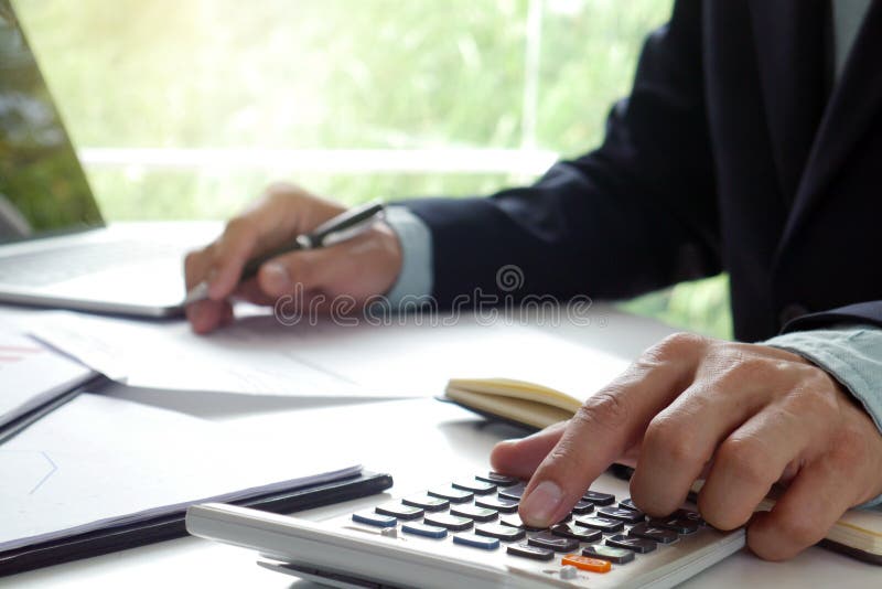 Men Use the Calculator and Take Notes with Calculations about the ...