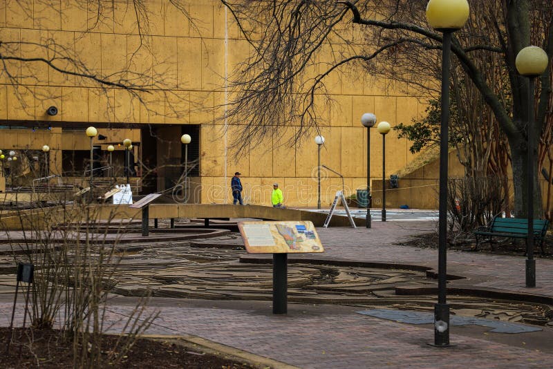 Men in Yellow Shirts Working Surrounded by a Brown Building and Light ...