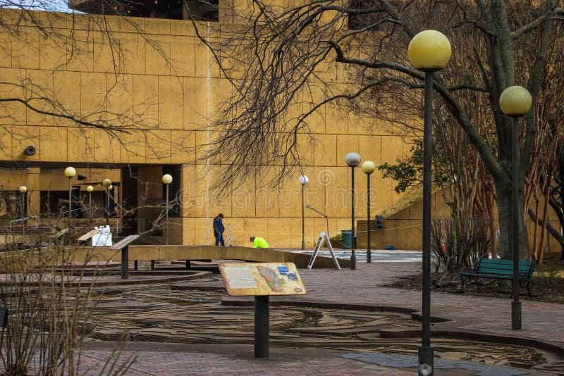 Men in Yellow Shirts Working Surrounded by a Brown Building and Light ...
