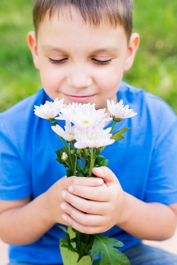 Menino Que Guarda Flores E Cheiro Foto de Stock - Imagem de azul ...