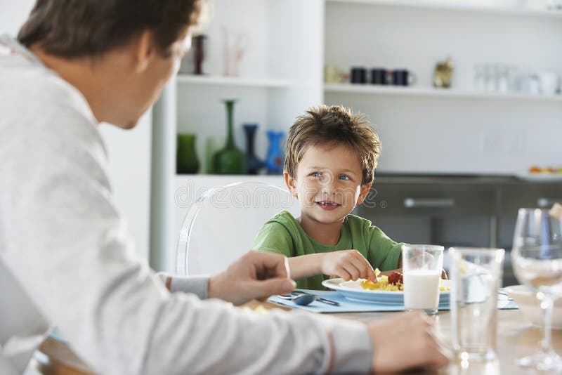 Menino Que Tem a Refeição Com Pai at Dining Table Imagem de Stock ...