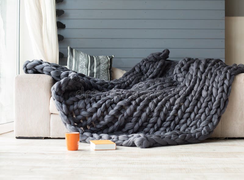 Merino Wool Grey Blanket Lying on White Sofa with an Orange Cup Stock ...
