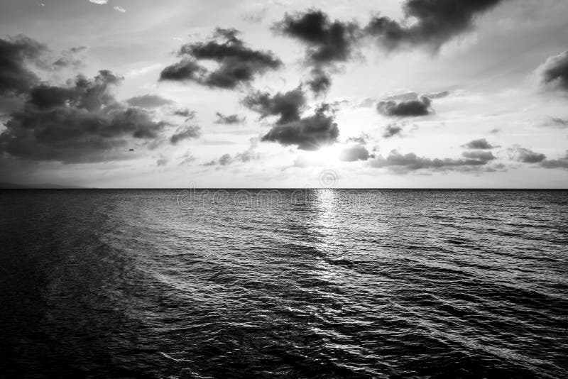 Mesmerizing Greyscale Shot of the Sun Setting Behind the Clouds Over ...