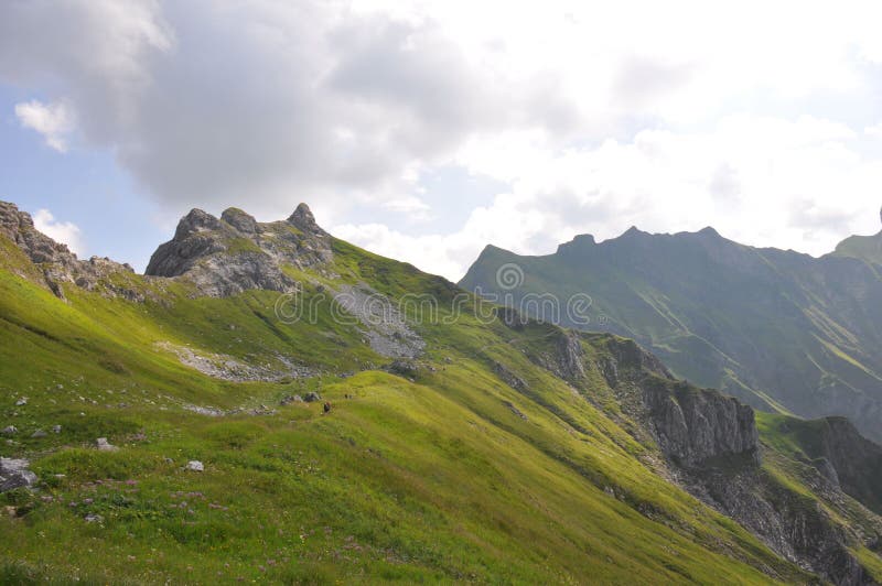 Mesmerizing Landscape of a Steep Slope Covered by Grass with Mountains ...