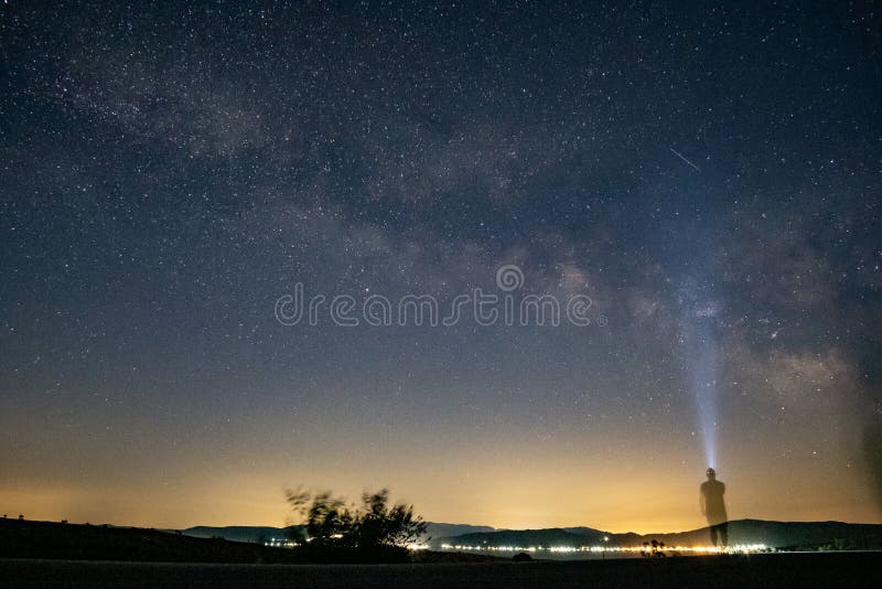 Mesmerizing Scene of a Man Pointing a Flashlight Towards the Night Sky ...