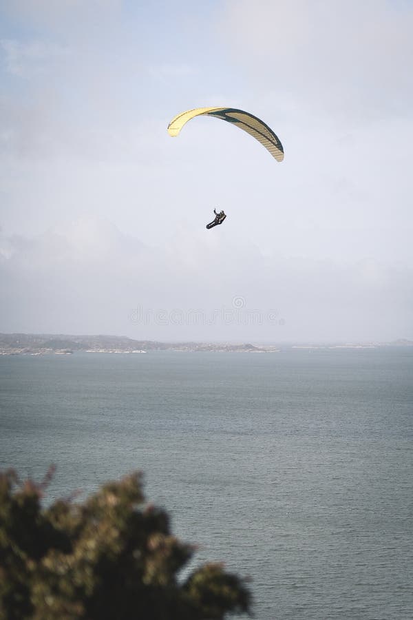. Mesmerizing View of Paragliding Over the Sea Water Under a Light Gray ...