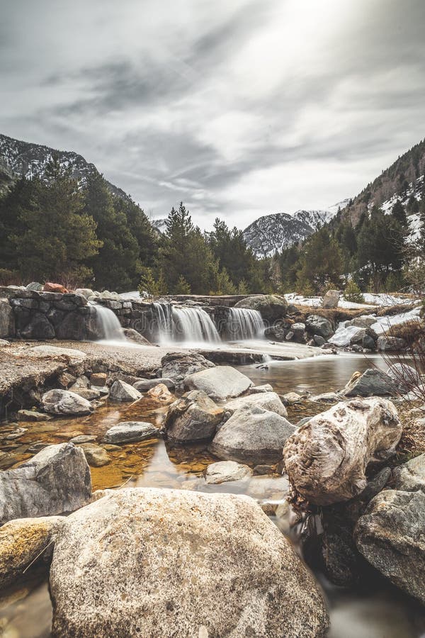 Mesmerizing View of a Waterfall Near a Forest and Mountains Stock Photo ...