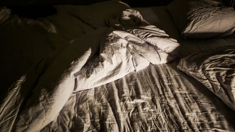 A Messy Bed with Wrinkled Sheets and High Contrast at Night Stock Photo ...