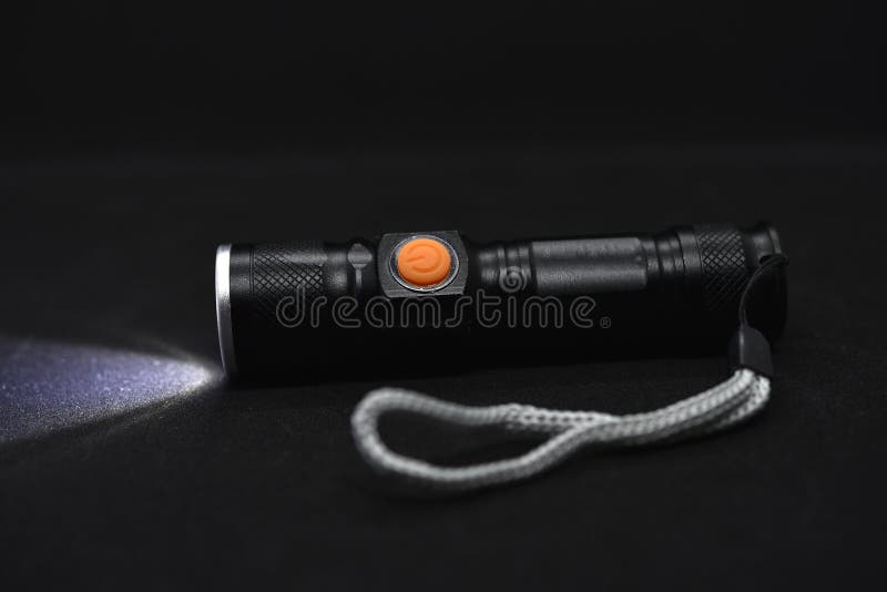 Metal Black Flashlight on a Black Background. Burning Pocket Flashlight ...