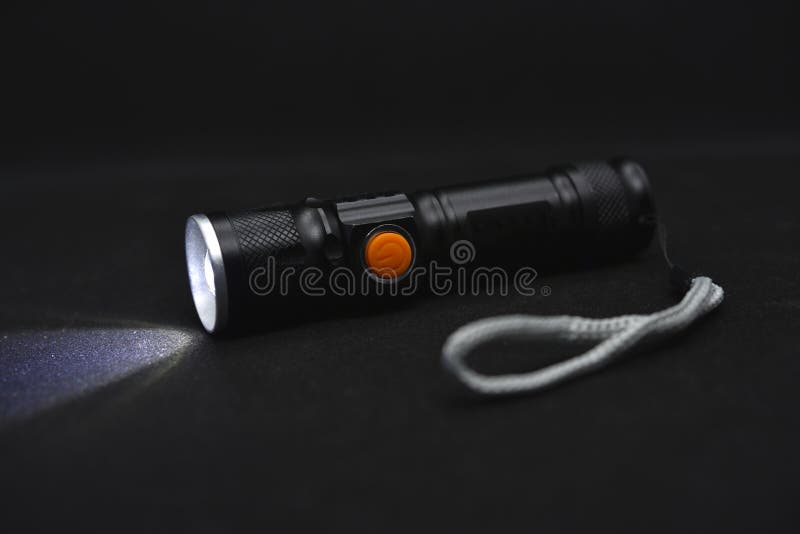 Metal Black Flashlight on a Black Background. Burning Pocket Flashlight ...
