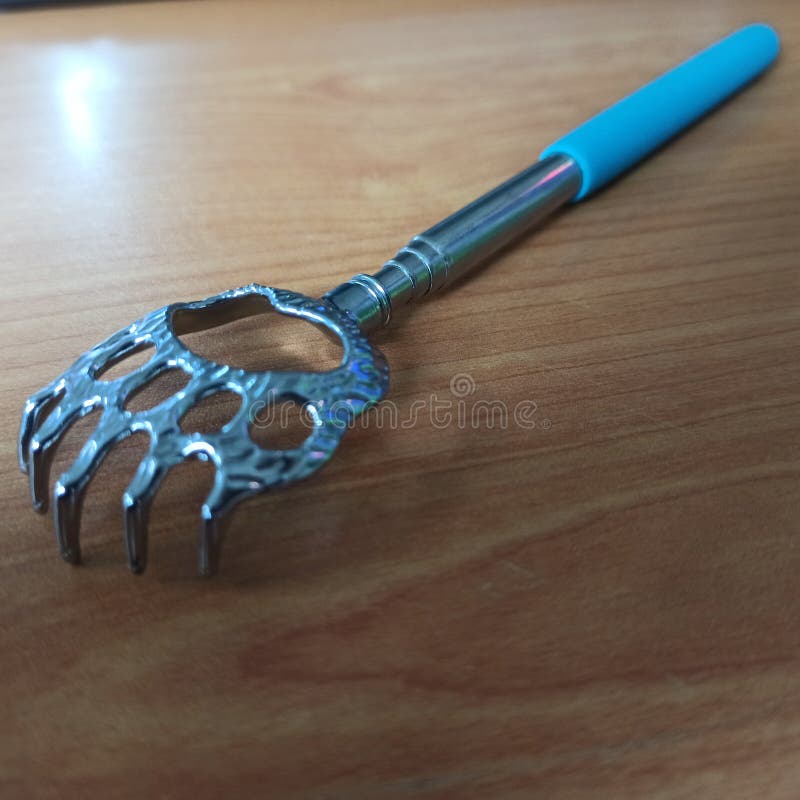 A Metal Claw Tool with a Teal-colored Grip, Resting on a Light-brown ...