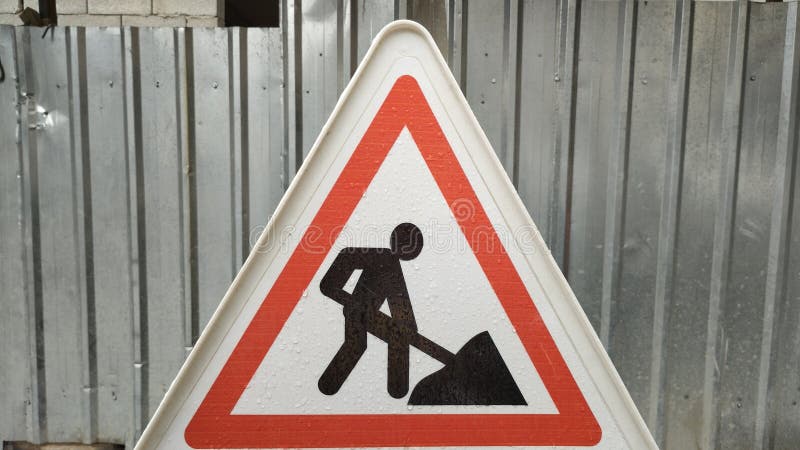 On the Metal Fence There is a Triangular Road Works Warning Sign Stock ...