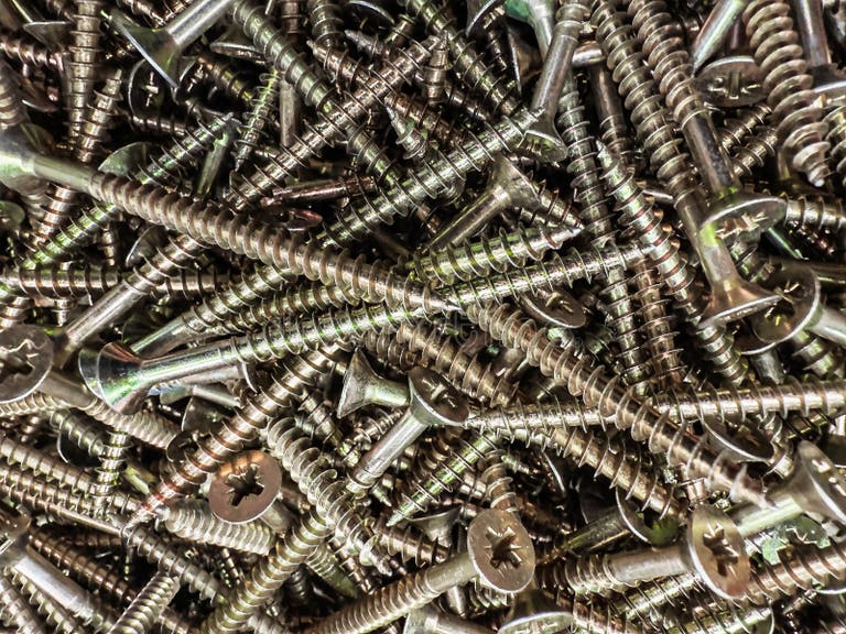 Metal Screws Scattered on a Workbench in a Workshop, Showcasing Various ...