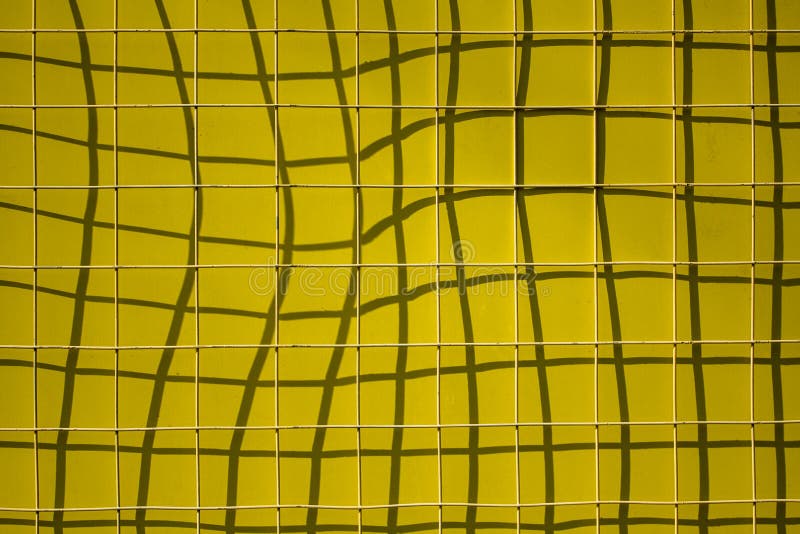 Metal Square Net with Curved Shadows on a Bright Yellow Wall Background ...