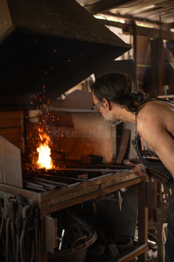 Metalworker Stoking the Fire in a Forge To Work Steel. Stock Image ...