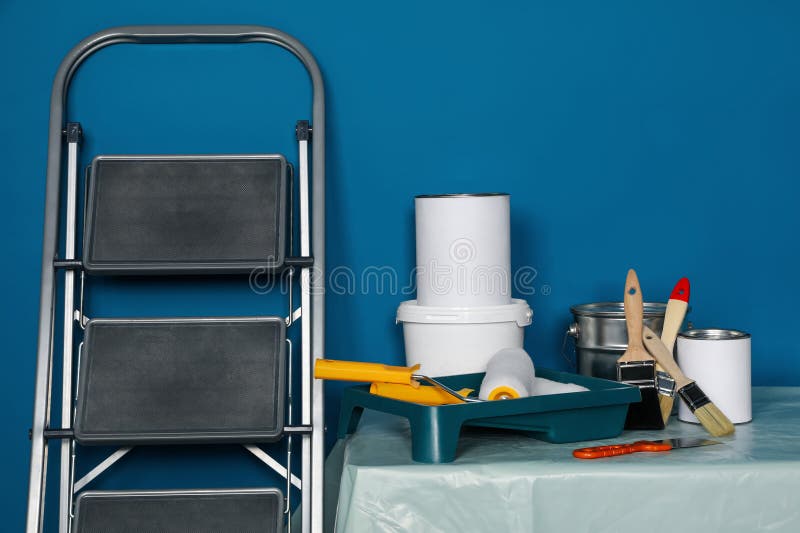 Metallic Folding Ladder and Painting Tools on Table Near Blue Wall ...