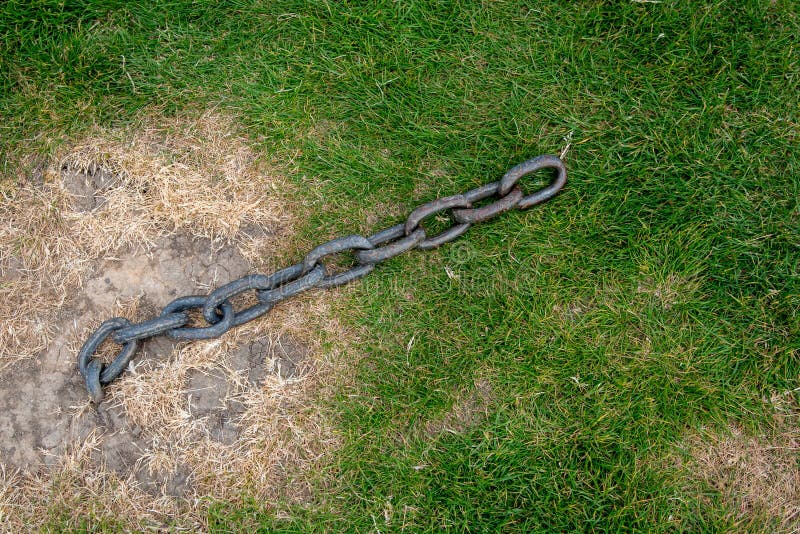 Metallic Industrial Iron Fastening Chain on a Green Grass. Security and ...
