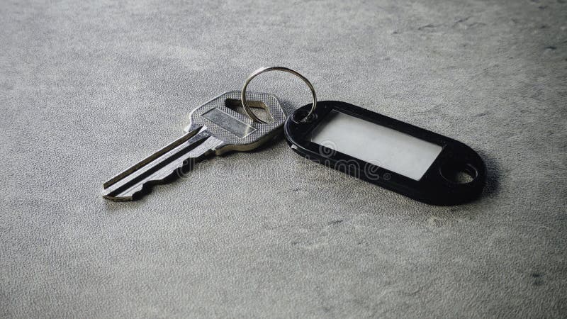 Metallic Key with Black Plastic Key Tag on Gray Surface Stock Image ...