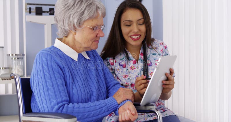 Mexican Caregiver Sharing Tablet with Elderly Patient Stock Photo ...