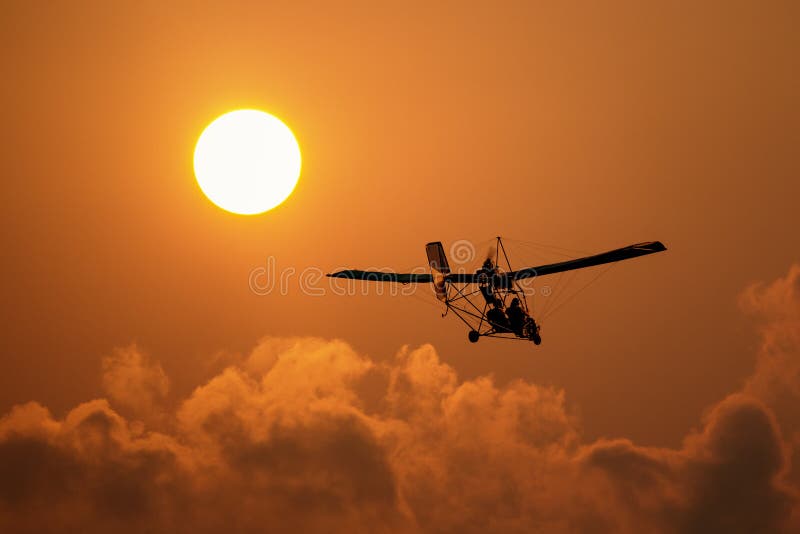 Microlight Aircraft with Two Passengers with the Sun and Cloud Stock ...