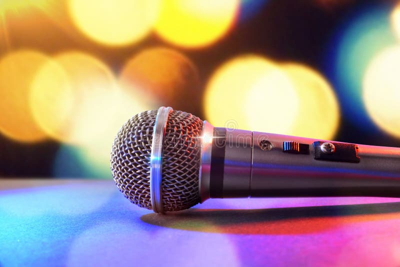 Microphone On Black Table And Colored Lights Background Stock Photo ...