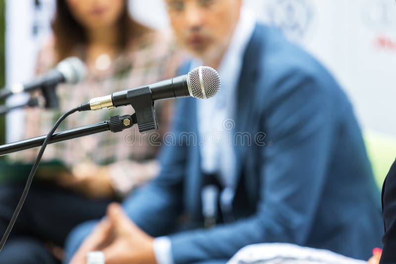 Public Speaking Concept. Microphone in Focus at Roundtable Meeting or ...