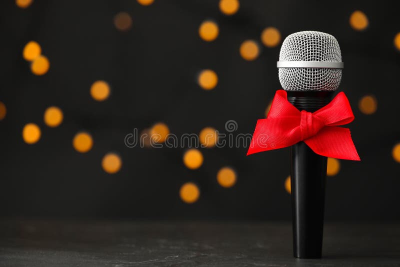 Microphone with Red Bow on Table Against Blurred Lights, Space for Text ...