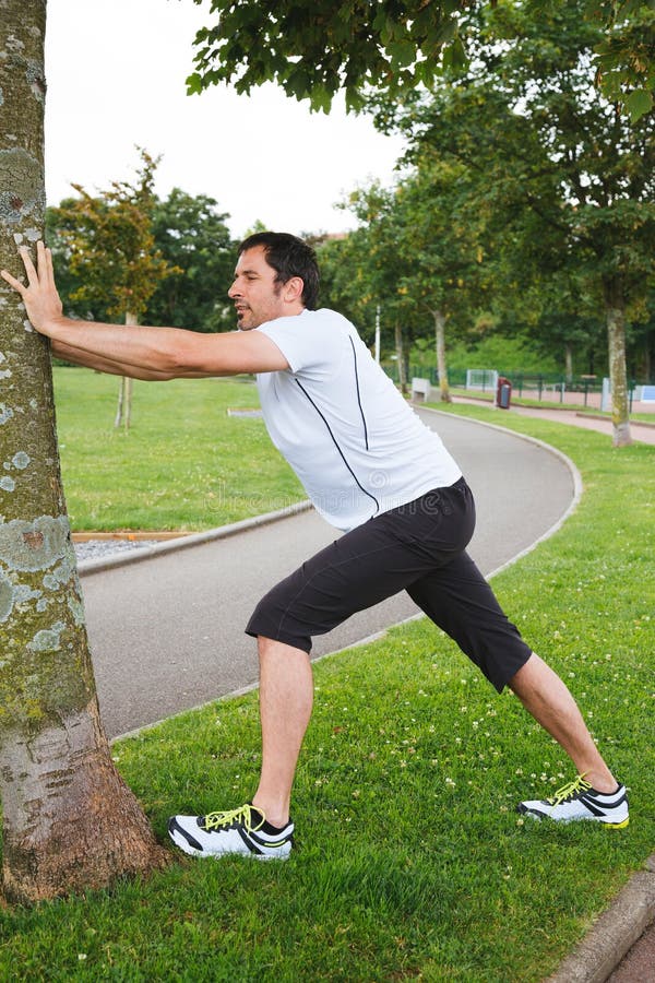 Mid Adult Man Doing Stretching Exercises Using a Tree Stock Photo ...