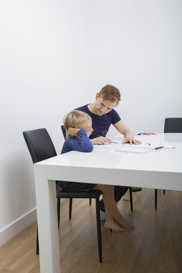 Mid Adult Man Helping Boy in Studies at Table Stock Photo - Image of ...