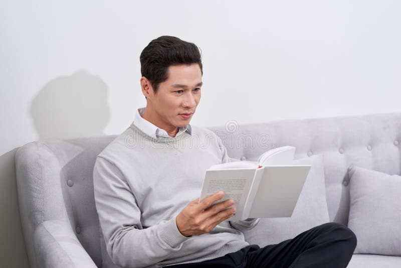 Mid Adult Man Reading Book While Sitting On Sofa At Home Stock Image