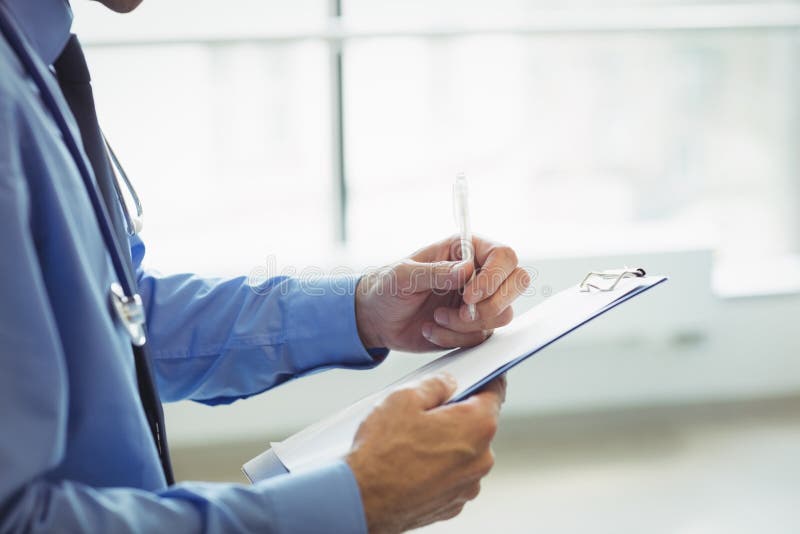 Mid Section of Doctor Writing on Clipboard Stock Photo - Image of ...