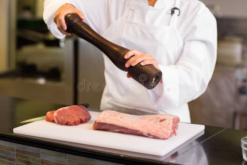 Mid Section of Female Chef Grinding Pepper Over Meat Stock Photo ...