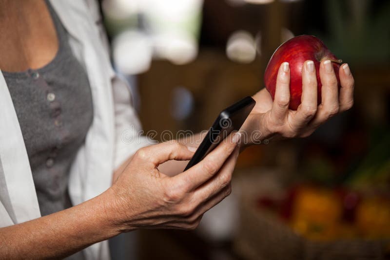 Mid Section of Female Costumer Holding Apple while Using Mobile Phone ...