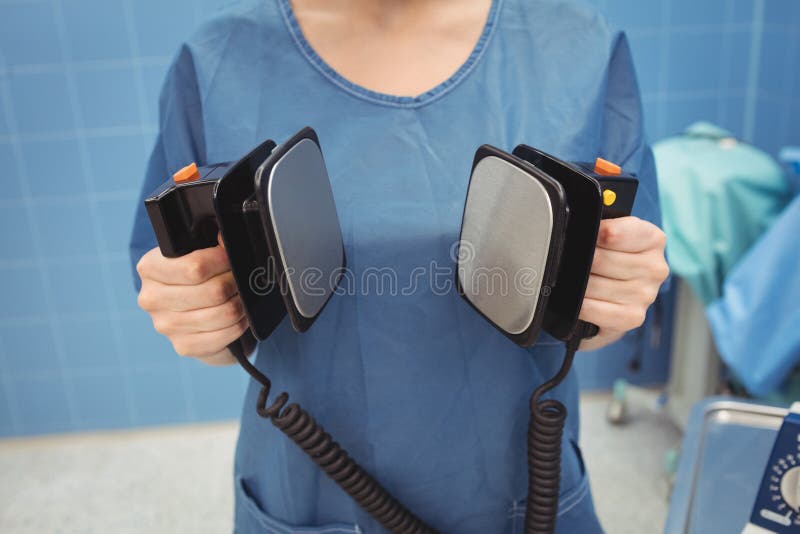Mid Section of Female Surgeon Holding Defibrillator Stock Image - Image ...